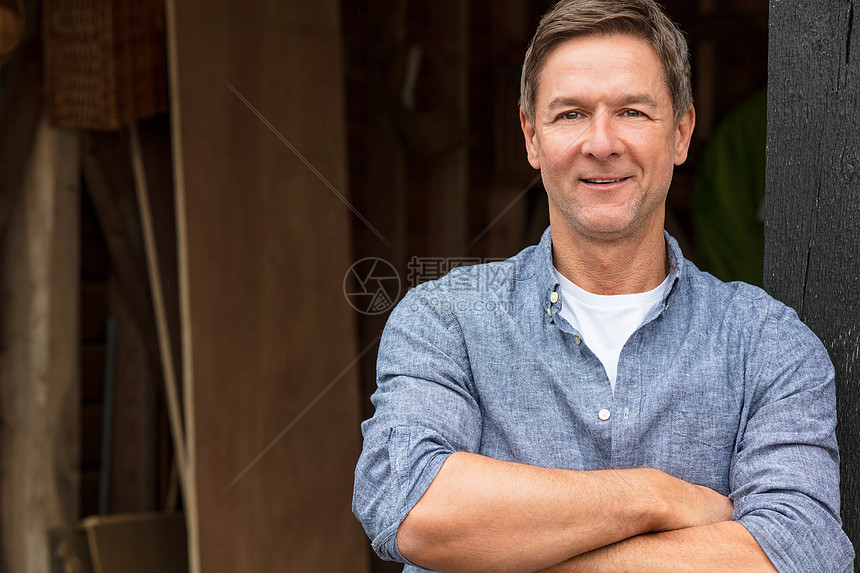 位吸引力成功快乐的中男子的肖像照片,男双臂交叉外,穿着件蓝色衬衫,车库棚子外高清图片下载-正版图片300172516-摄图网