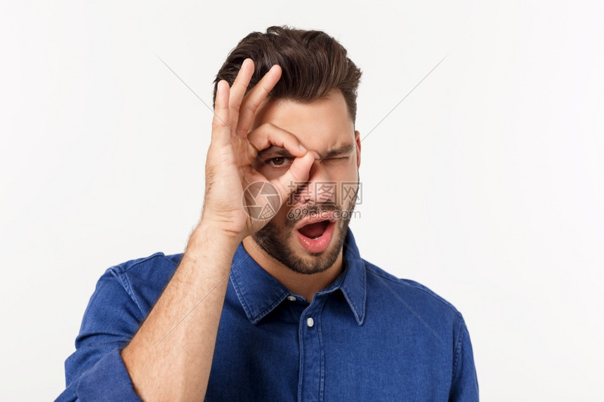 长着胡子的年轻英俊男用惊讶的脸部眼睛透过手指看震惊地表情令人难以置信高清图片下载-正版图片303653342-摄图网