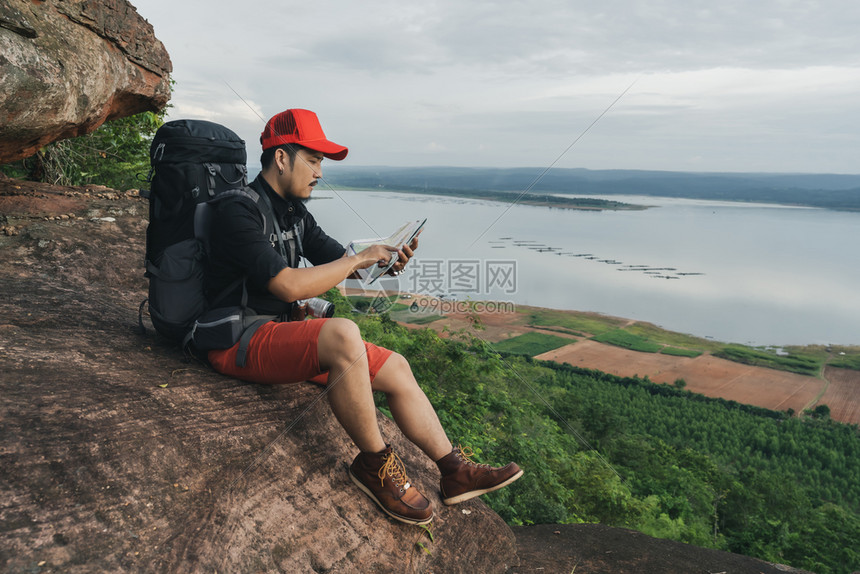 背着包的人旅行者看着悬崖边缘的岩石山顶的高清图片下载-正版图片307070005-摄图网