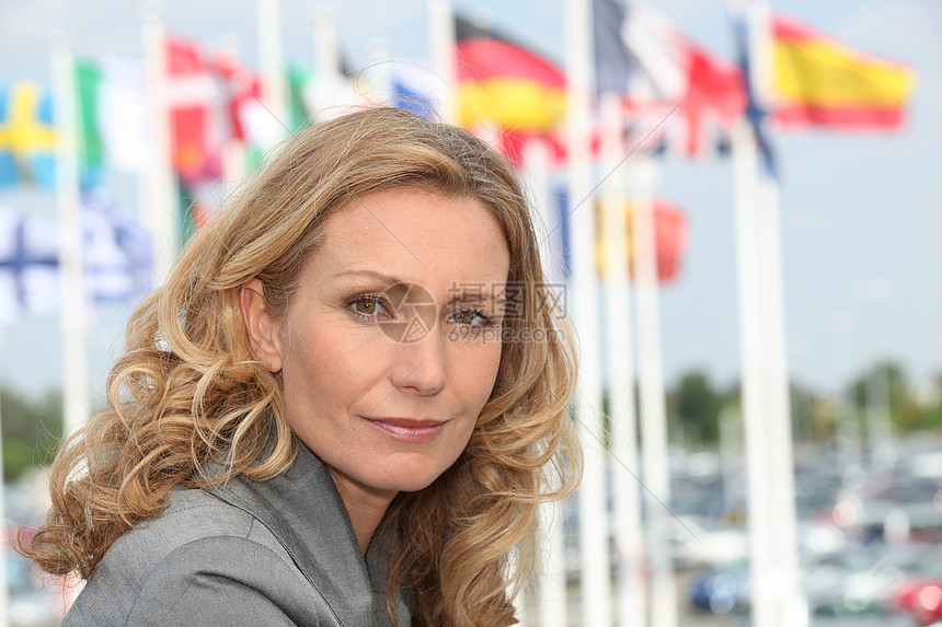 在背景中挂有旗帜的妇女旅行国会微笑员工导演女士商业飞机场倾斜首脑高清图片下载-正版图片321244331-摄图网