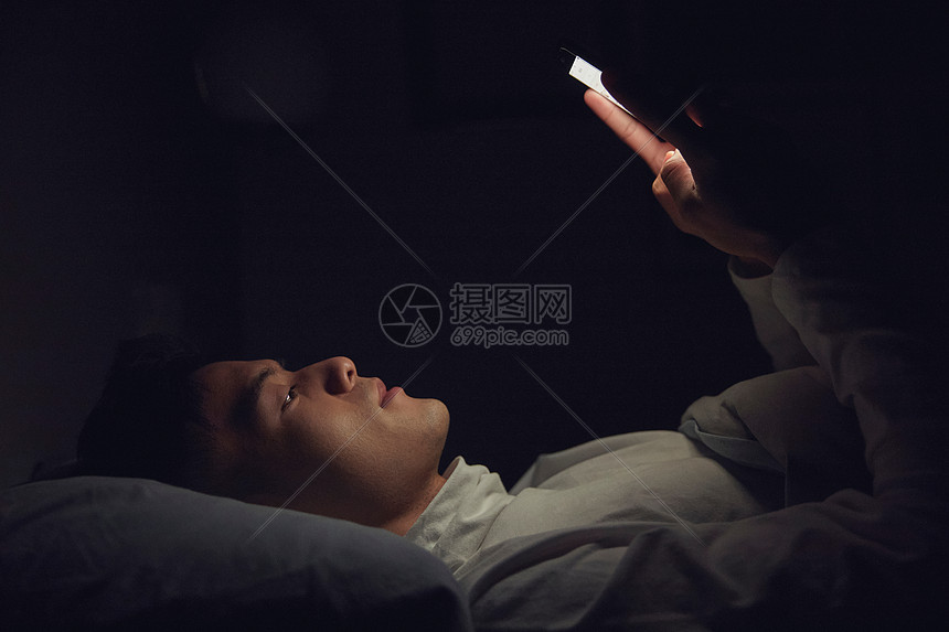 年轻男士深夜躺在床上玩手机高清图片下载 正版图片501687443 摄图网