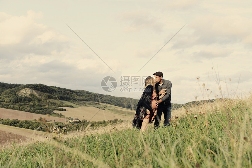 浪漫的怀孕中年夫妇在乡村山坡上接吻高清图片下载 正版图片501883386 摄图网