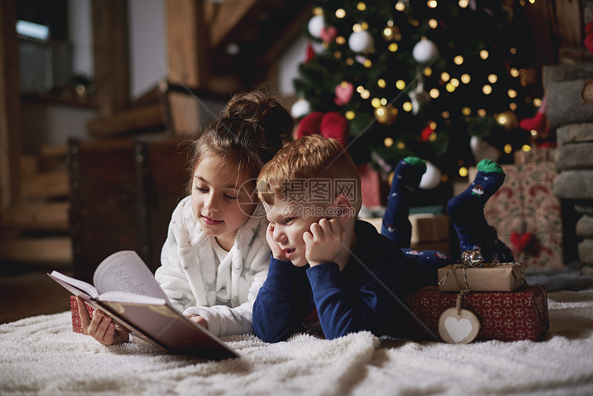 女孩和男孩在圣诞树旁边看书高清图片下载-正版图片501885371-摄图网