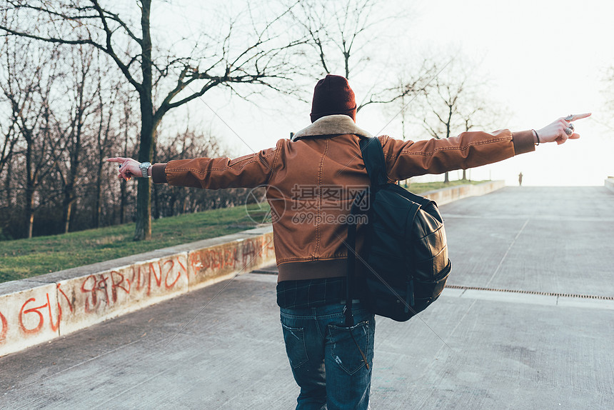 年轻时尚潮男张开双臂在公园里行走的背影高清图片下载-正版图片501891794-摄图网