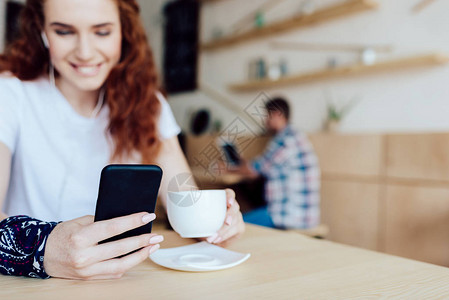 在咖啡馆里用智能手机喝杯咖啡的年轻人微笑高清图片下载-正版图片503486897-摄图网