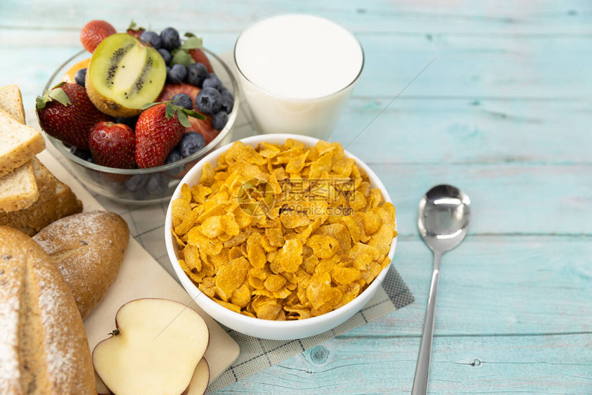 面包水果草莓蓝莓猕猴桃玻璃杯中的牛奶和垫子和木桌上的碗里的麦片高清图片下载-正版图片503945048-摄图网
