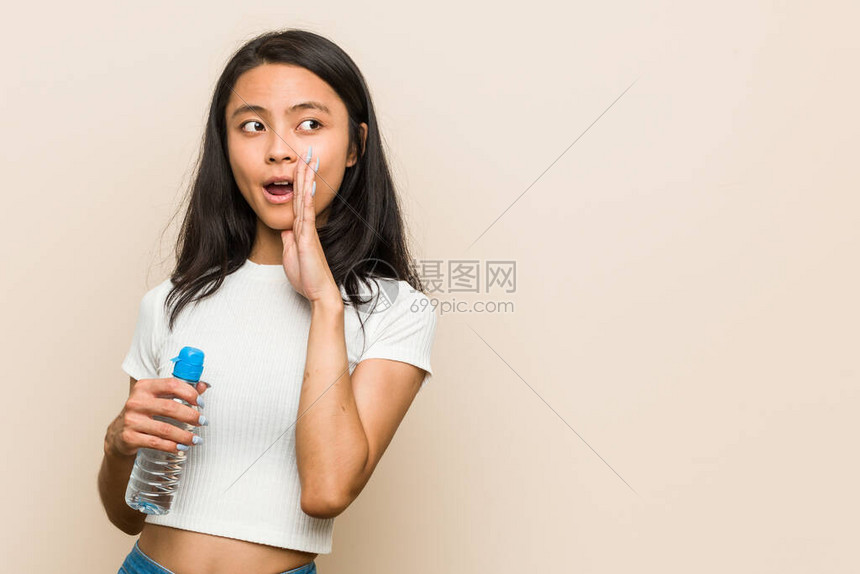 拿着水瓶的年轻亚洲女人正在说一个秘密热辣的新闻高清图片下载 正版图片504087941 摄图网