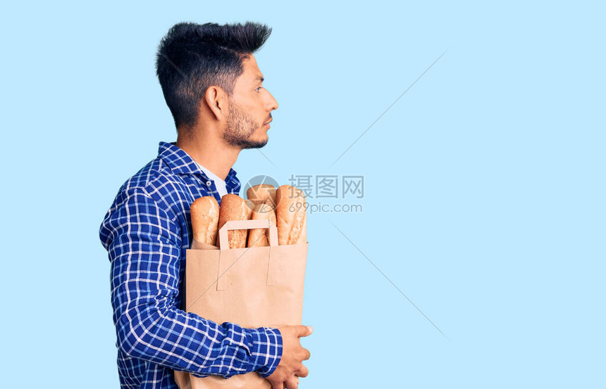 长得帅的拉丁裔美国年轻人拿着纸袋和面包靠边看高清图片下载 正版图片504244177 摄图网