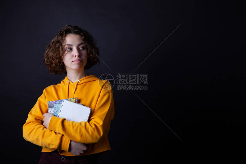 穿着黄色连帽衫和笔记本在工作室里摆姿势的年轻白人高中女生高清图片下载 正版图片504376448 摄图网
