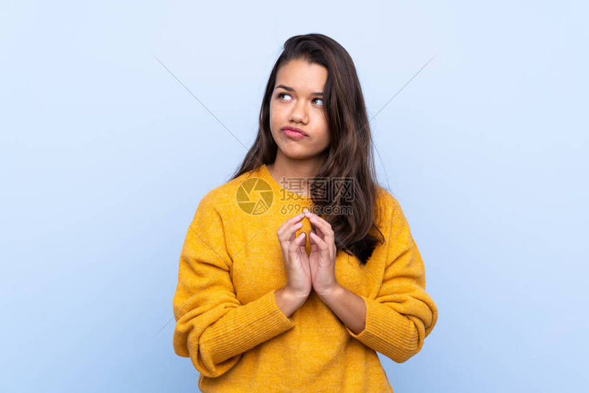 穿着毛衣的哥伦比亚年轻女孩在孤立的蓝色背景下高清图片下载 正版图片504431699 摄图网