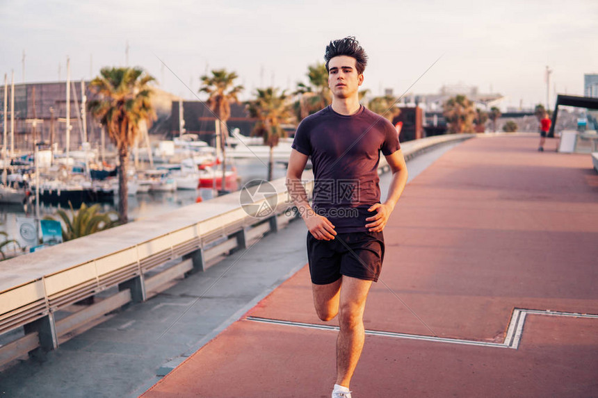 年轻运动员在公园里跑步背景有摩天大高清图片下载-正版图片504511193-摄图网