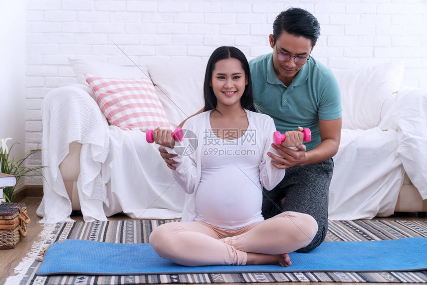 丈夫照顾妻子怀孕帮助在家客厅锻炼怀孕夫妇保高清图片下载 正版图片504521391 摄图网