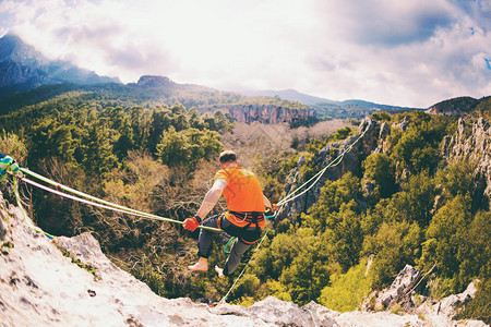 高线山脉的背景一个人坐在拉长的吊索上走钢丝的表演Highliner在深渊上保持平衡运动员摔倒高清图片下载-正版图片504529130-摄图网