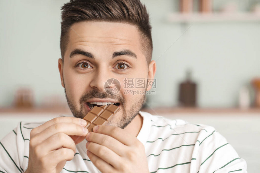 英俊的年轻人在厨房里吃巧克力高清图片下载 正版图片504590989 摄图网