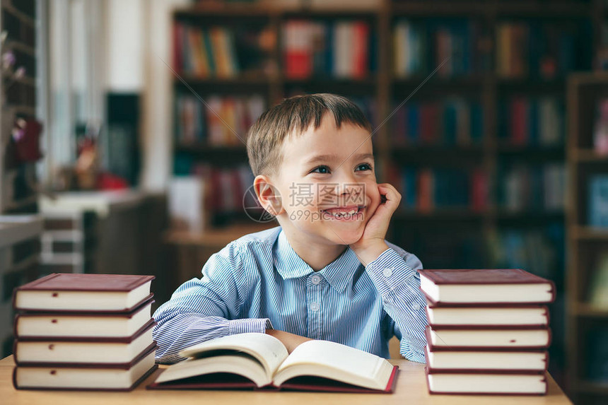 图书馆桌上的单身男孩喜欢看书男孩左手放在脸颊上的正面图像欧洲男孩探索书籍学生喜欢讲课教育高清图片下载-正版图片505257465-摄图网