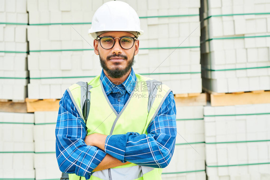 身穿硬帽和腰衣的英俊长胡子男在站水泥砖堆旁时高清图片下载-正版图片505872332-摄图网