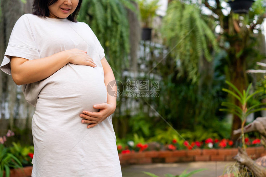 孕妇在照顾孩子的同时在家感到快乐年轻的准妈抱着婴儿在怀孕的肚子里产前护理和高清图片下载 正版图片506126518 摄图网