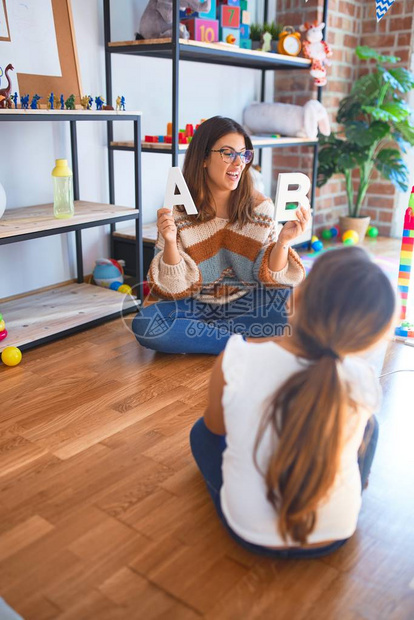 美丽的老师在幼儿园的很多玩具旁教幼儿字母表高清图片下载 正版图片506363237 摄图网