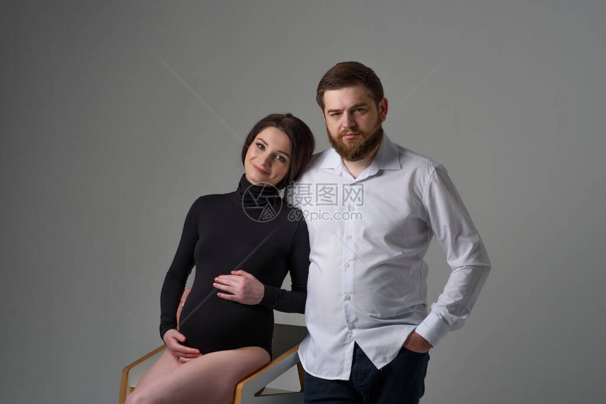 孕妇和她丈夫正拥抱着灰色背景高清图片下载-正版图片506652327-摄图网