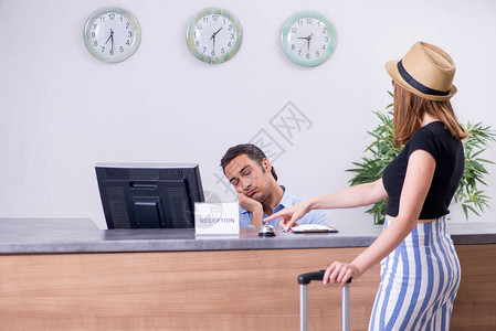 年轻英俊的商人与站在现代酒店大堂柜台接待处的女接待员交谈并高清图片下载-正版图片506737670-摄图网