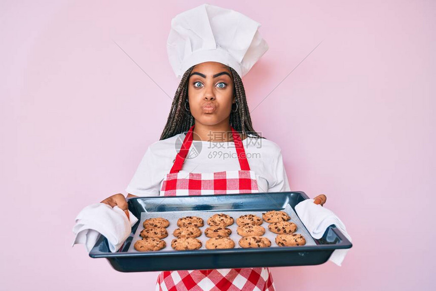 身穿面包师制服的非洲年轻女拿着自制曲奇饼高清图片下载-正版图片506739554-摄图网