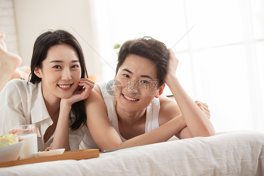 快乐的年轻情侣趴在床上高清图片下载 正版图片507654861 摄图网