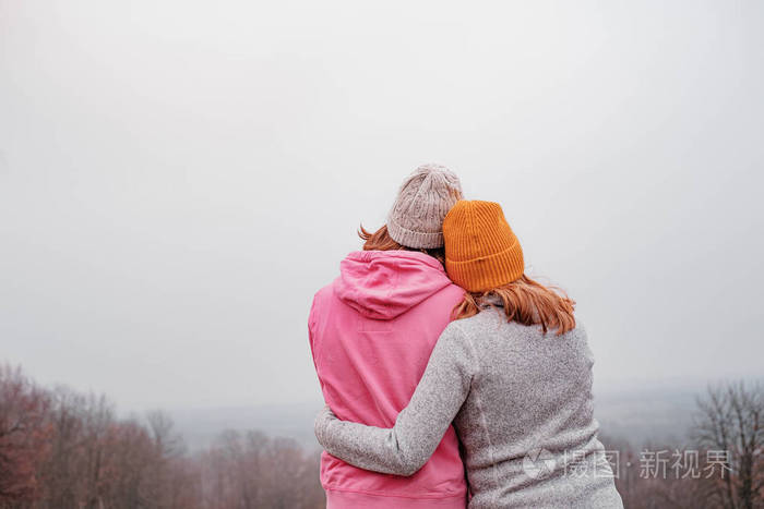 Two young woman in casual clothes hug each other on autumn sky b照片-正版商用 ...